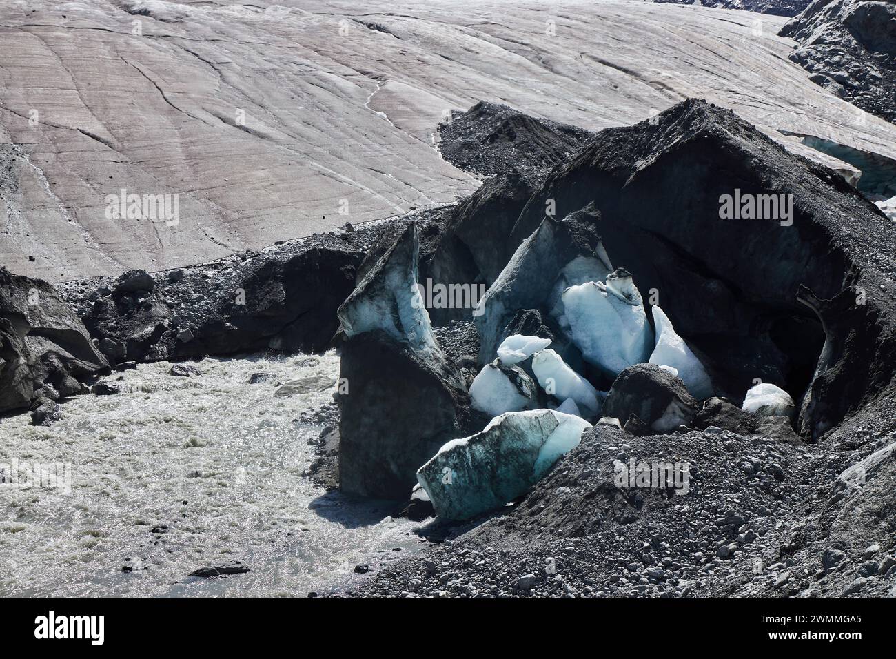 Jagged ice emerges from beneath a blanket of dirt and rock at the edge ...