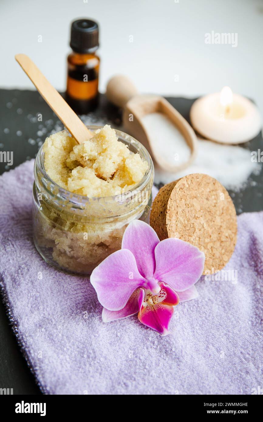 Handmade sugar body scrub in glass jar. Burning candle and pink orchid ...