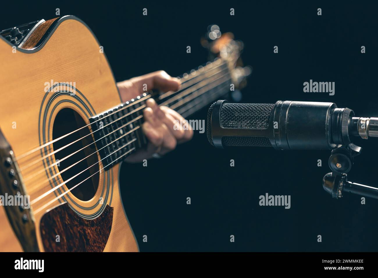 Male musician playing acoustic guitar behind microphone in recording ...