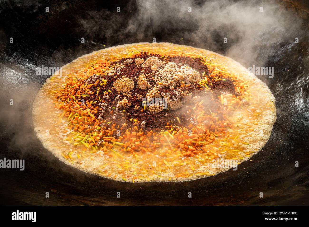 Cooking pilaf on fire in a large cauldron, stewing lamb, vegetables ...