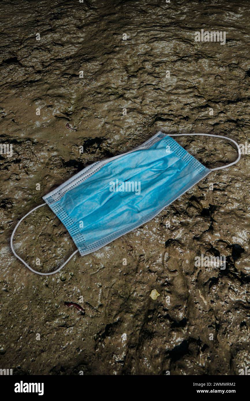 Minimalist still life of a disposable reusable blue face mask discarded ...