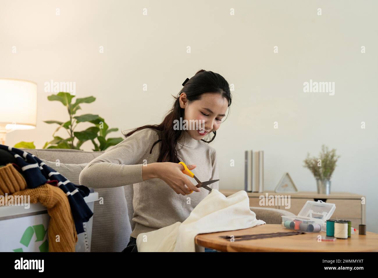 Woman repairs sews reuses fabric from old clothes economical reuse. DIY ...