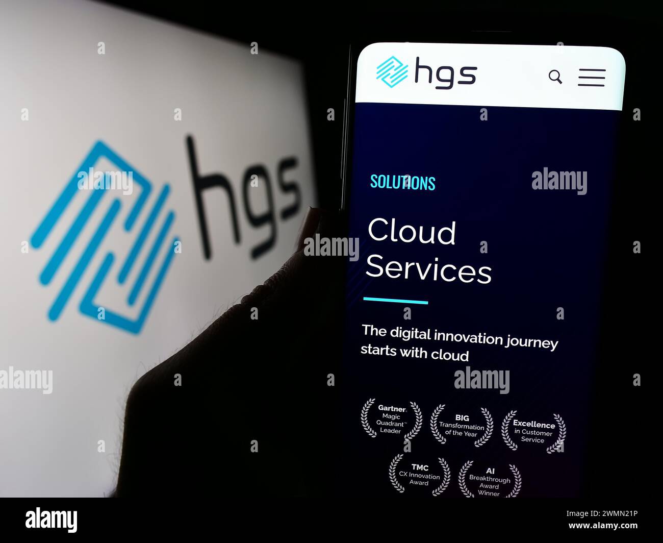 Person holding mobile phone with website of Indian company Hinduja ...