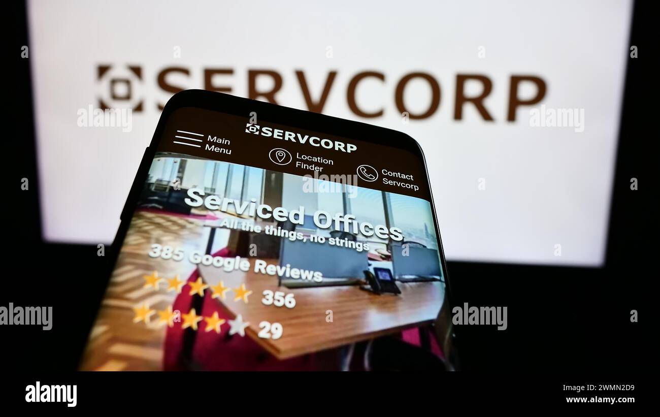 Mobile phone with website of Australian workspace solutions company Servcorp Limited in front of ...