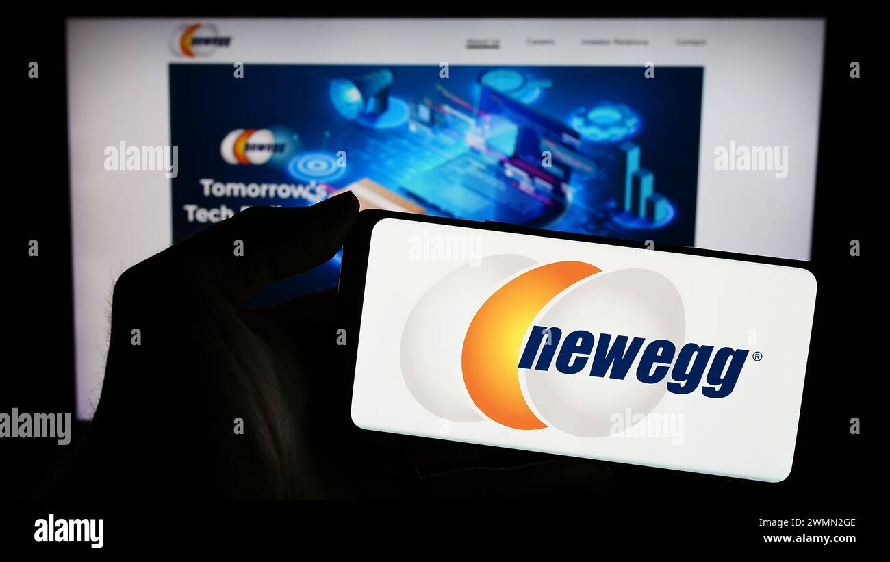 Person holding mobile phone with logo of American computer retail company Newegg Commerce Inc ...