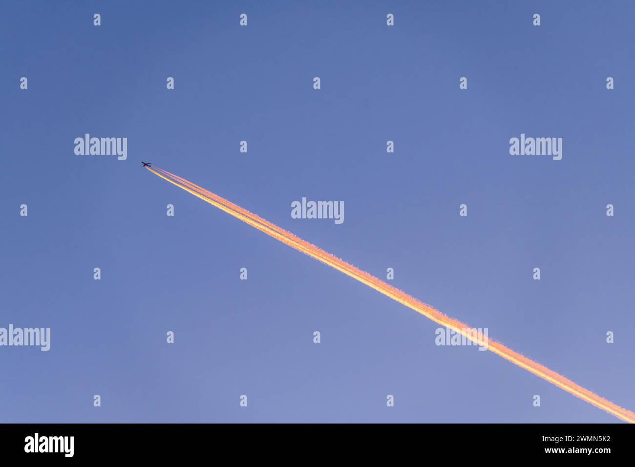 A Boeing 747 jumbo jet flying high in a cloudless blue evening sky ...