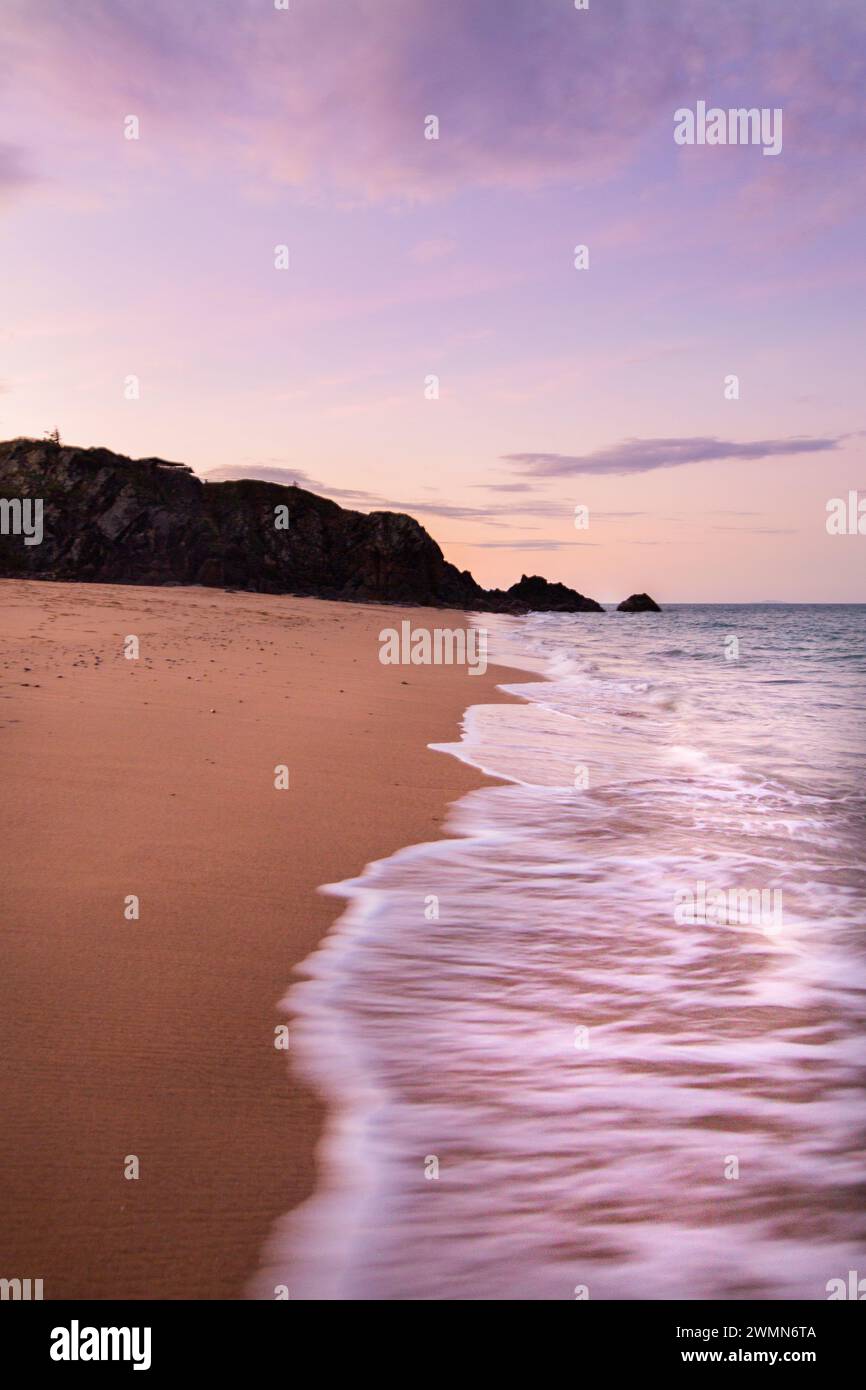 A wave on beach at sunset with rocky background in Mackay, Queensland ...