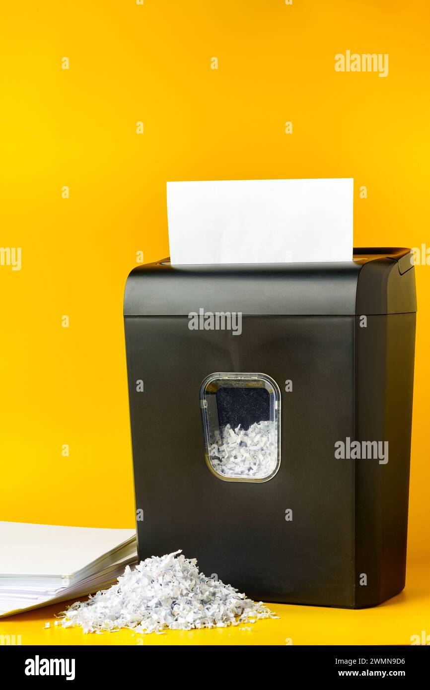 Office paper shredder on yellow studio background Stock Photo - Alamy