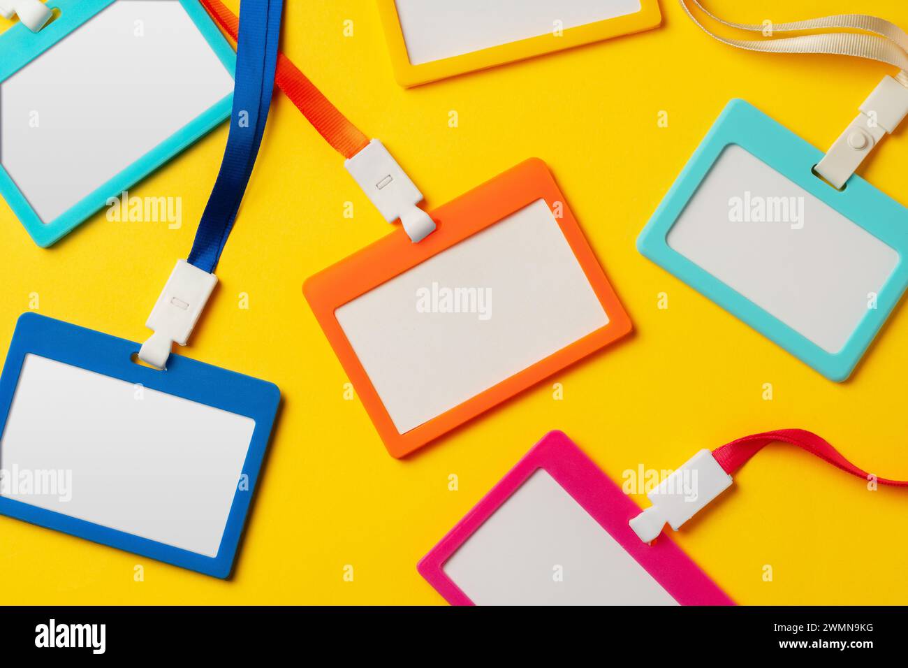 Colored blank nametags on strings on yellow background Stock Photo - Alamy