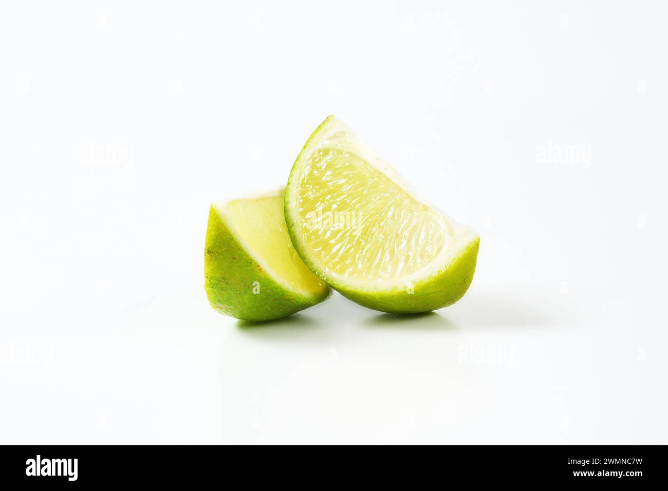 Two lime fruit quarters on white background Stock Photo - Alamy
