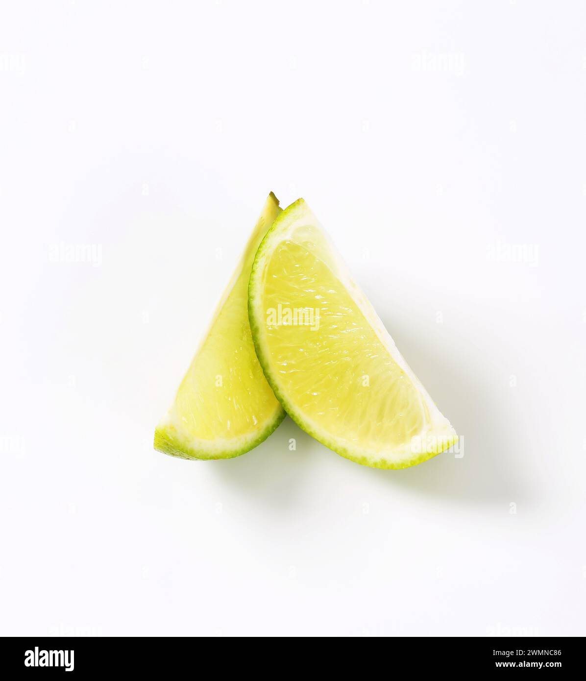 Two lime fruit quarters on white background Stock Photo - Alamy