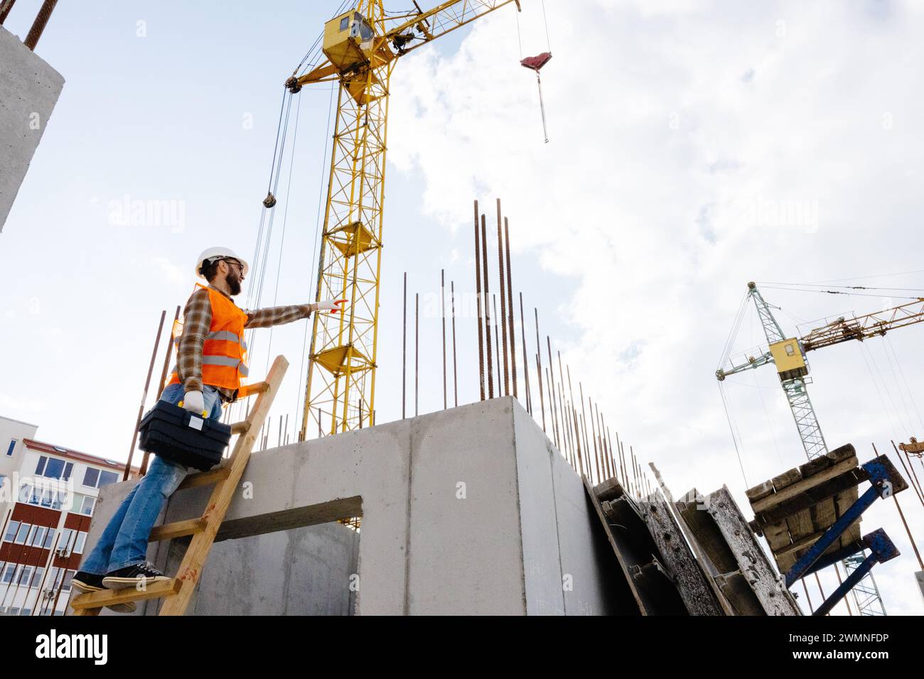 Maintenance worker man with safety helmet and orange vest climbing wood ...