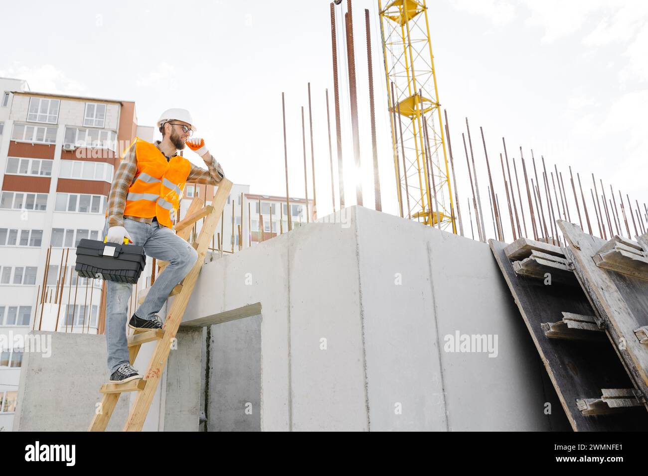 Maintenance worker man with safety helmet and orange vest climbing wood ...
