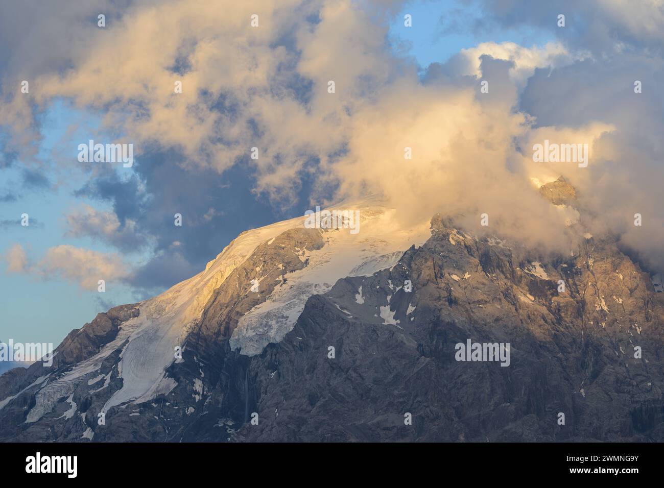 The Ortler Alps near Stelvo Pass at sunset in summer, clouds around the ...