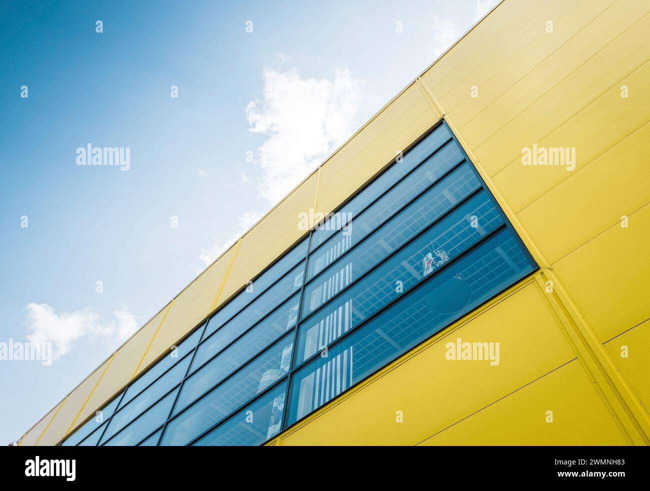 Wall of yellow building with big blue window. Clear blue sky in the ...