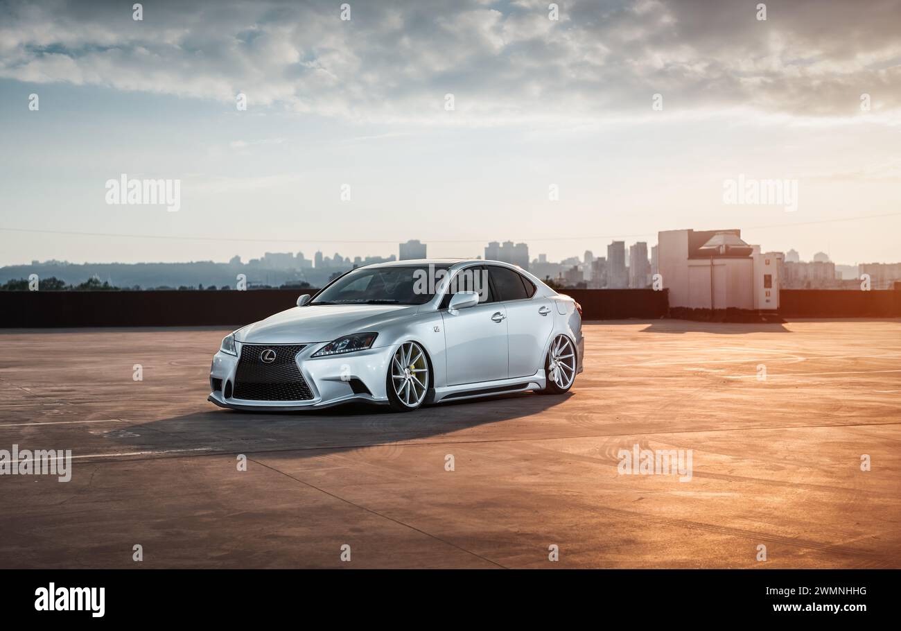 Lexus IS sedan parked on top level of parking garage. Golden sunset ...