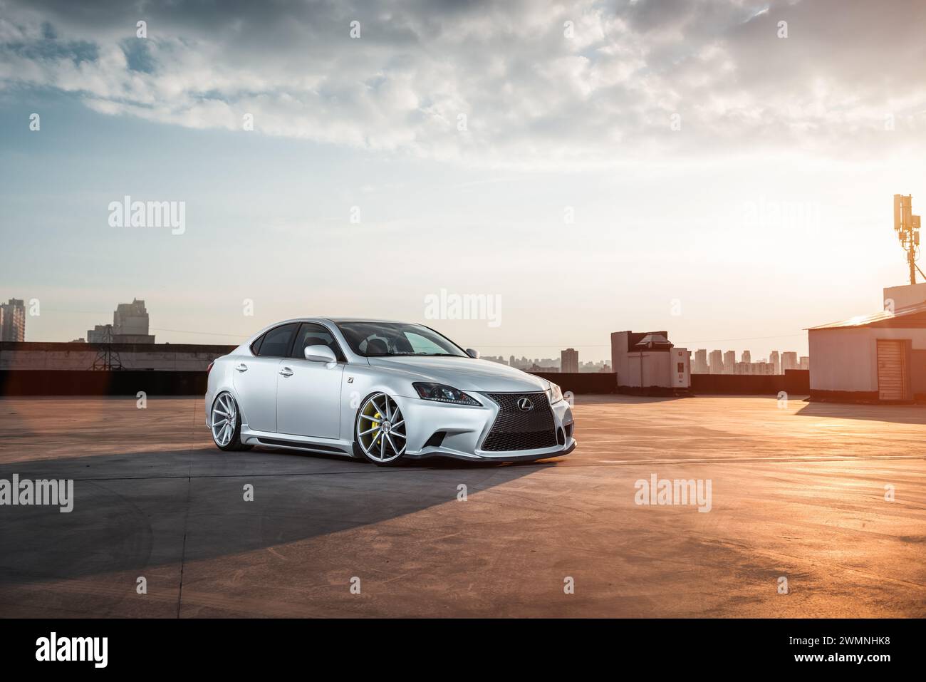 Lexus IS sedan parked on top level of parking garage. City skyline in ...