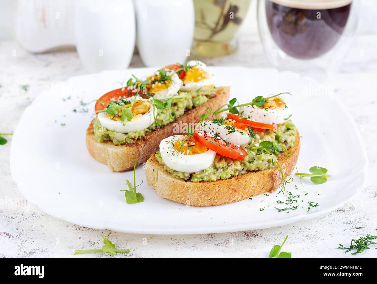 Delicious toast with avocado, boiled egg, tomatoes and microgreen on a ...