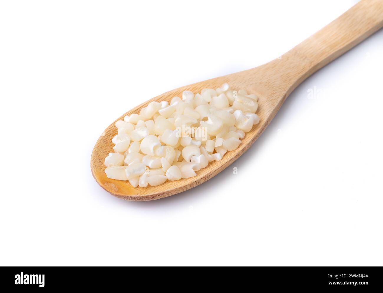 Dried canjica, hominy or white corn in a spoon isolated over white ...