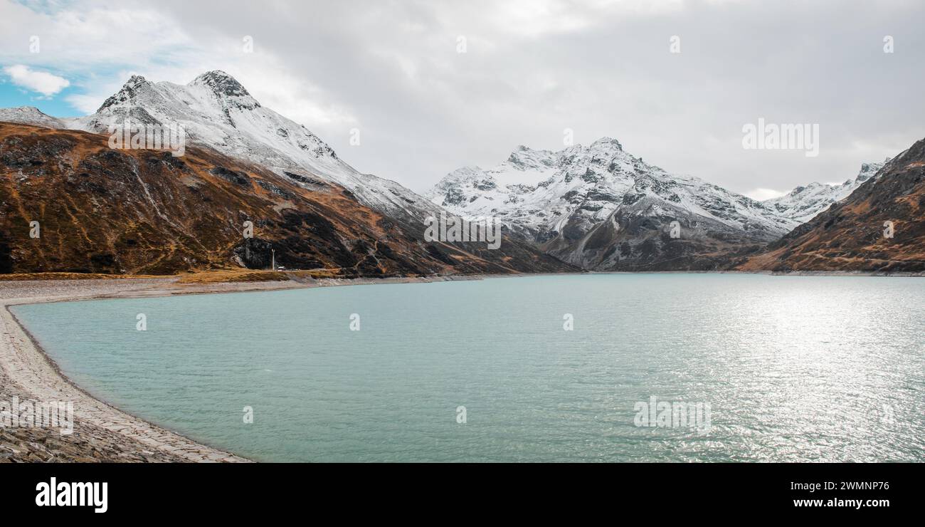 Reservoir with turquoise water in Silvretta Alps. Snow capped rusty ...