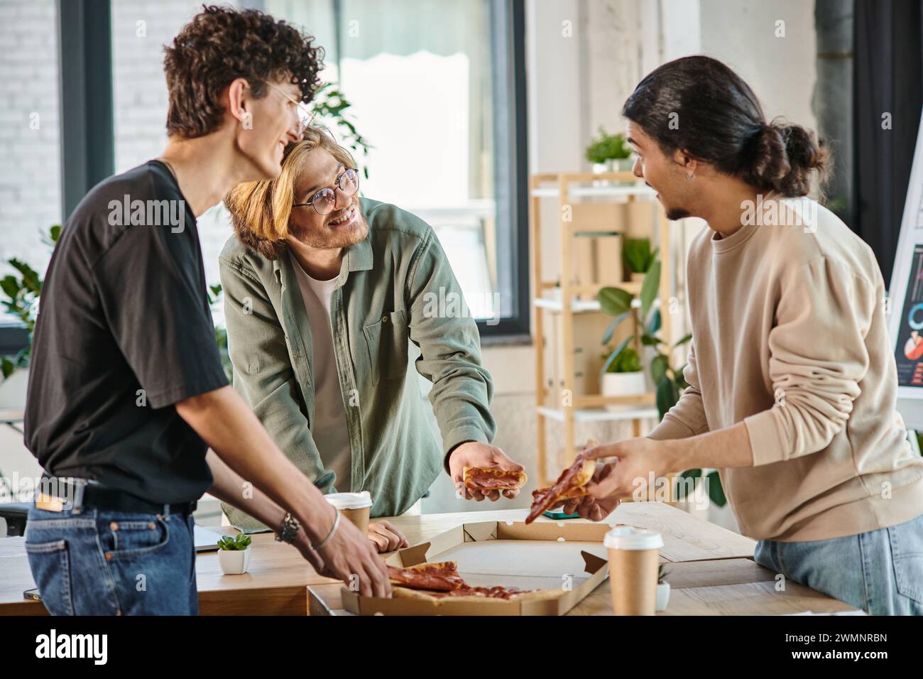 young men enjoying a pizza lunch break in a friendly and relaxed office ...