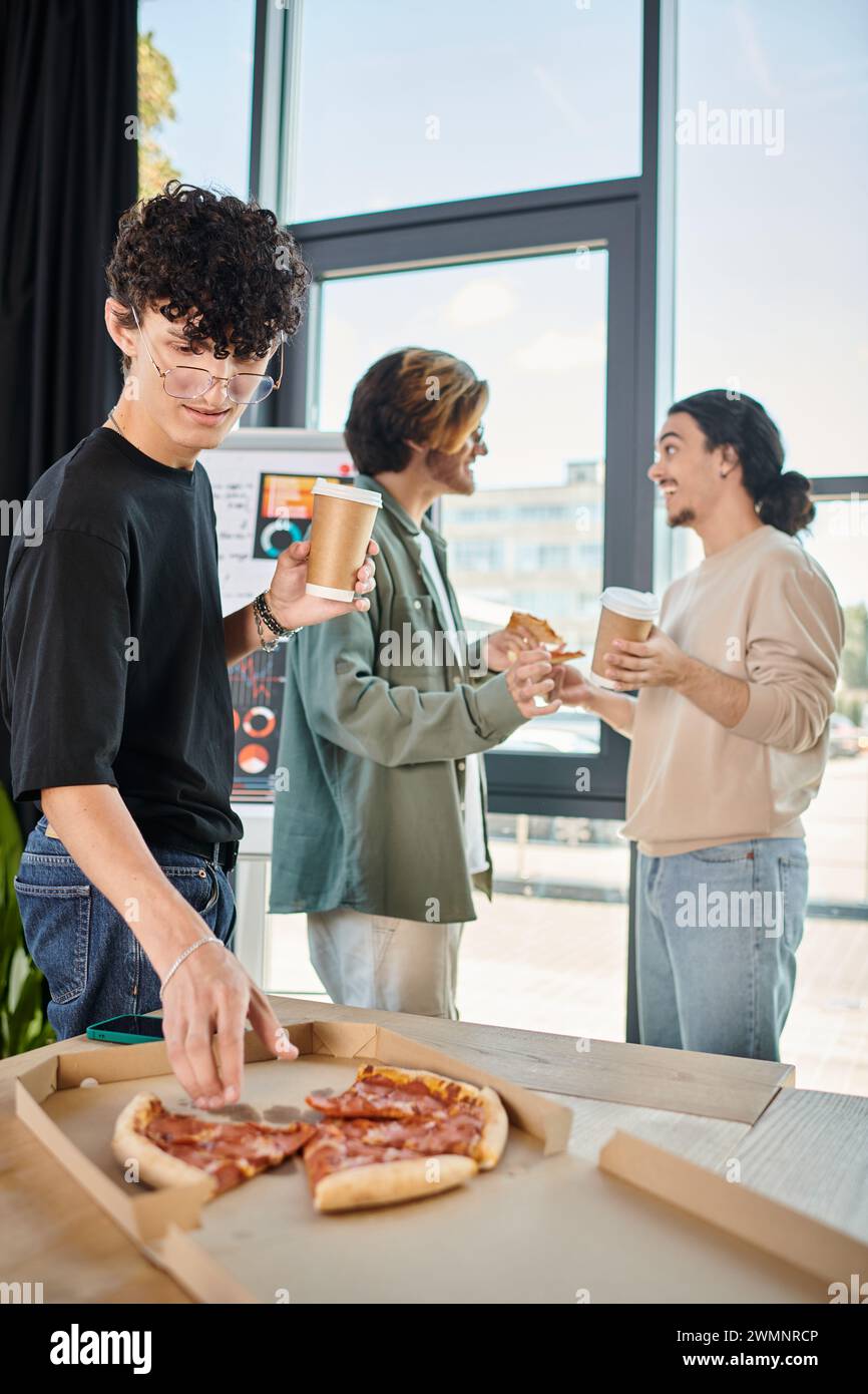 curly team member with coffee taking slice of pizza in friendly office ...