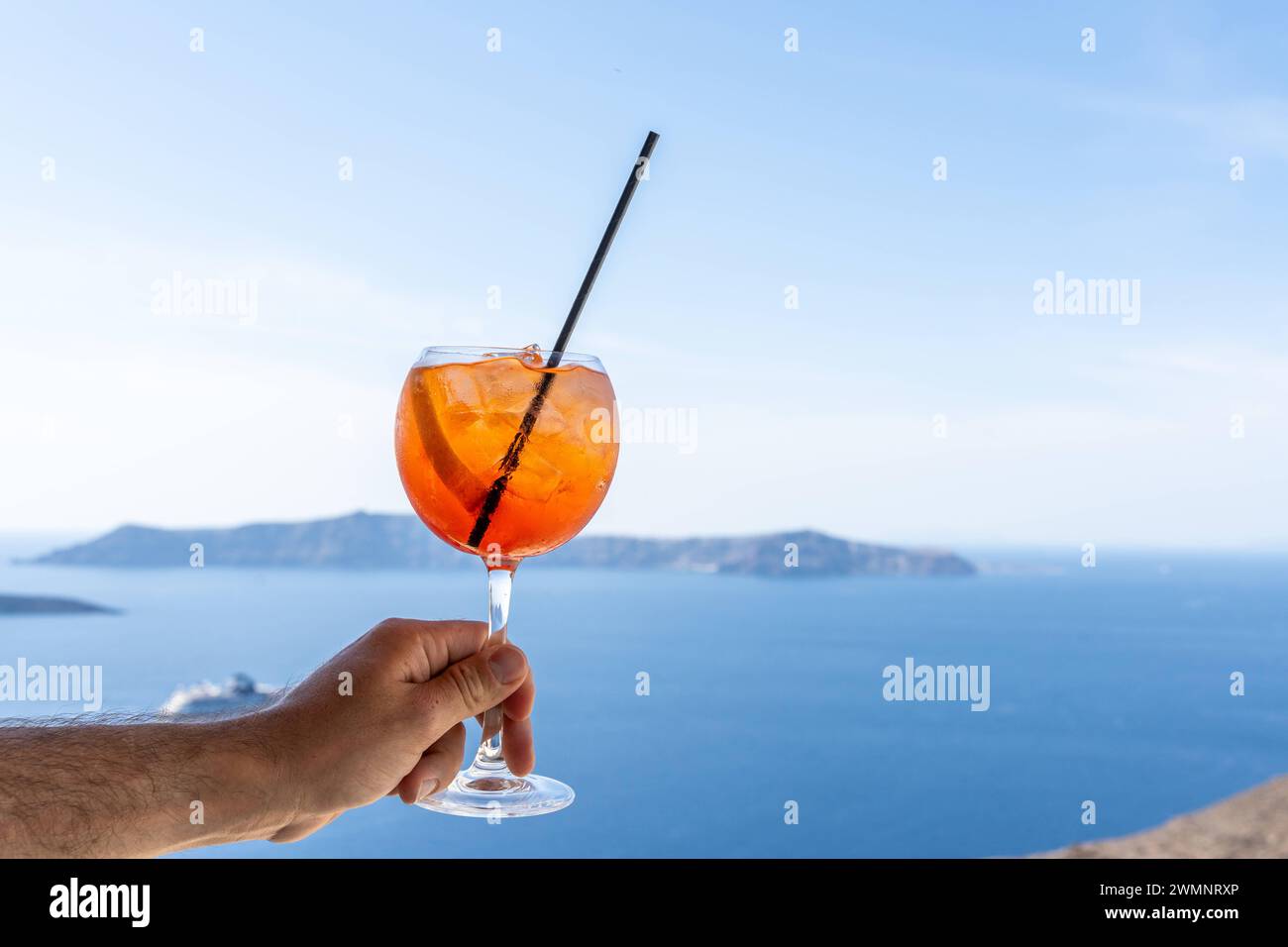 Santorini, Greece - September 20, 2023: A man holds a long drink ...