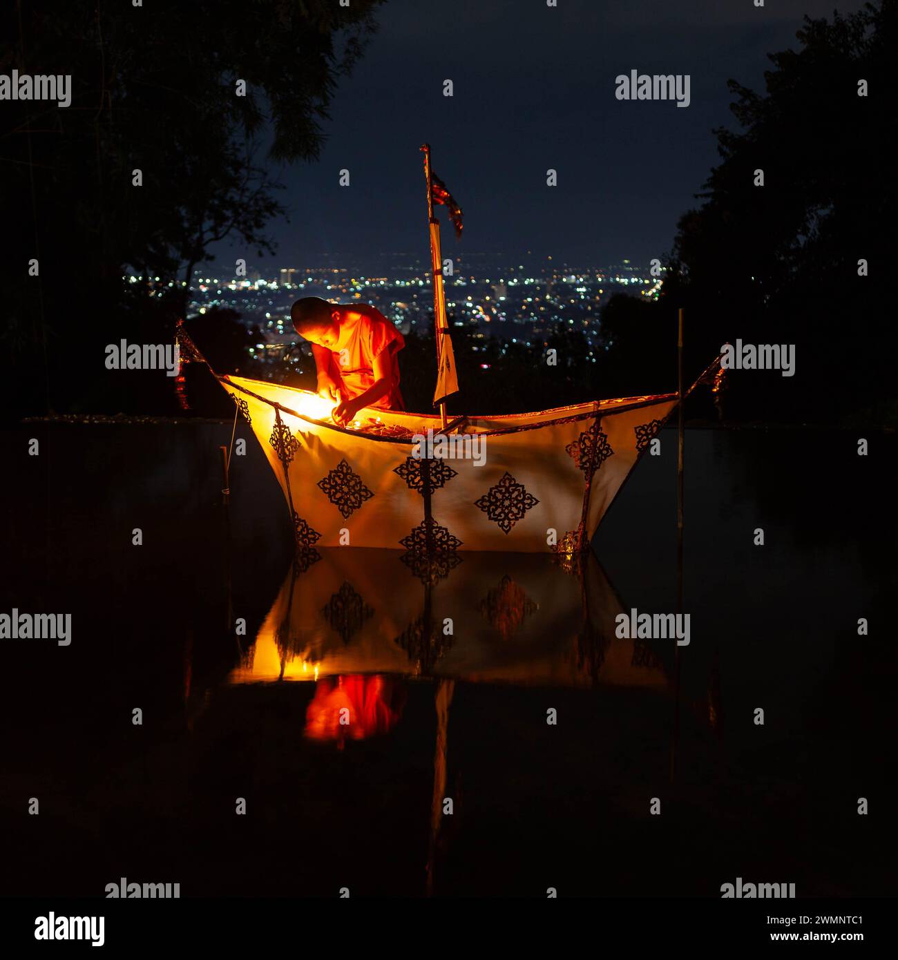 Buddhist monk lights candle on the river at Wat Pha Lat forest temple ...