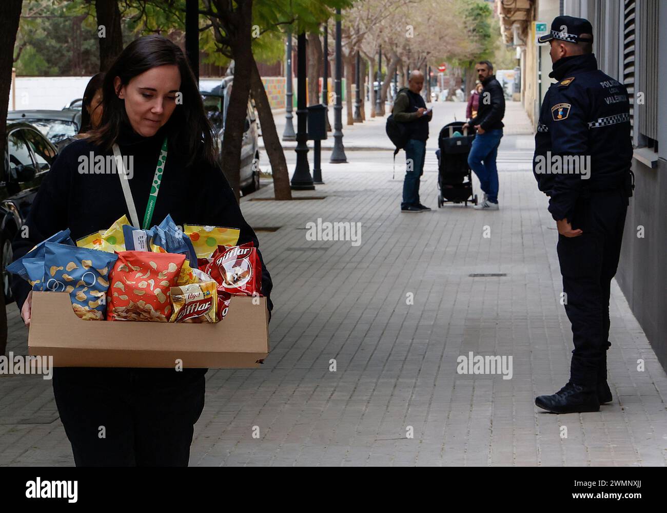 A woman holds a box of food in the vicinity of the building where ...