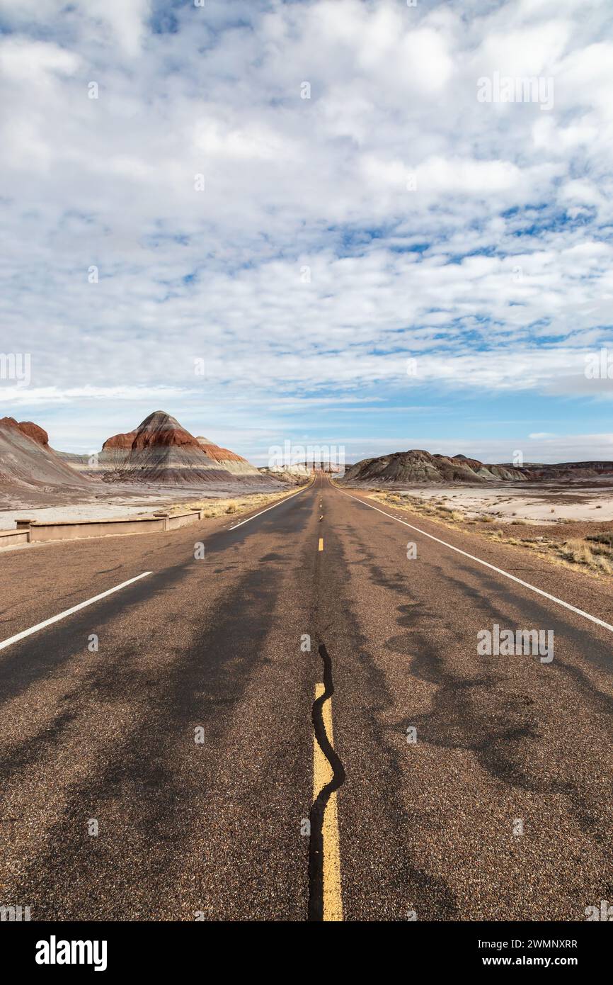 A long road through the Painted Desert, with rock formations on both ...