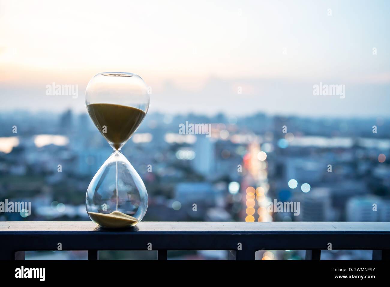 A tall hourglass on a city balcony overlooking the skyline Stock Photo ...