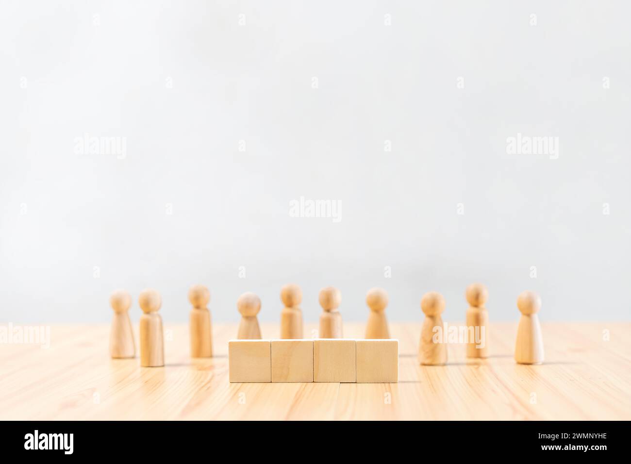 The wooden toy figures encircling wooden block on white background ...