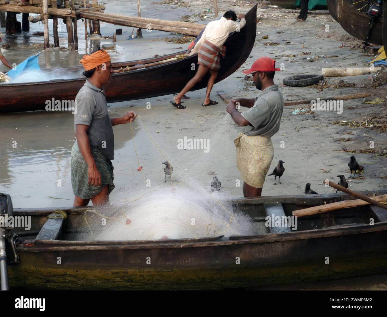 India, Kerala, Cochin: two fishermen fix their fishing nets at the end ...