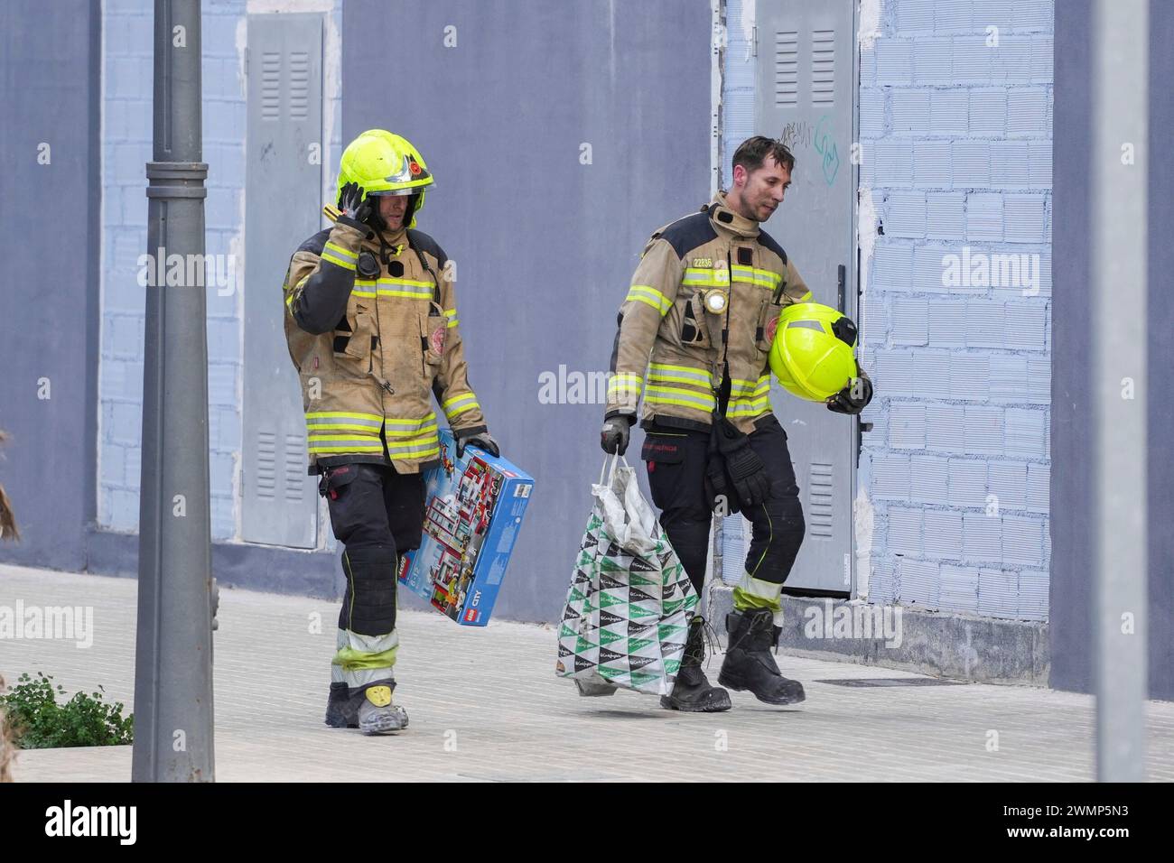 Firefighters carry belongings of those affected by the building fire ...
