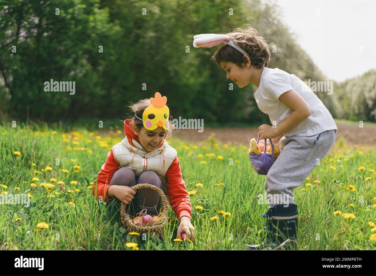 Two children hunt for Easter eggs in a spring garden. Easter tradition ...