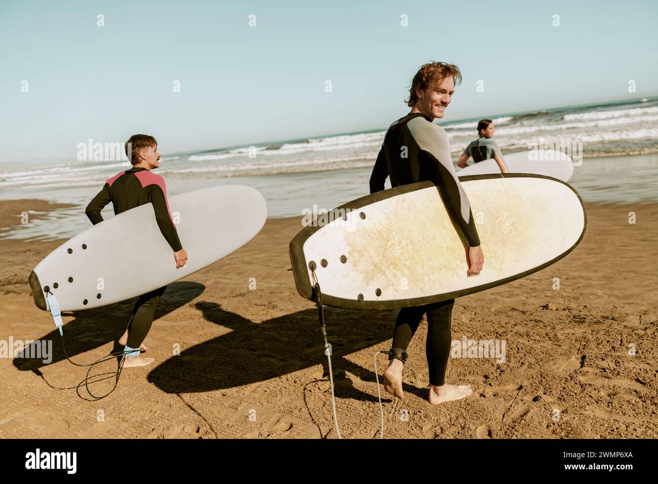 Group of surfers with surfboards in wetsuit are walking on the beach ...