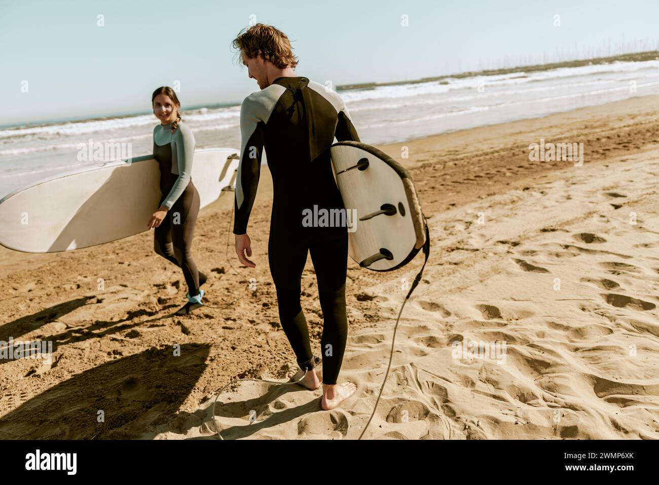 Back view of surfers with surfboards in wetsuit are walking on the ...