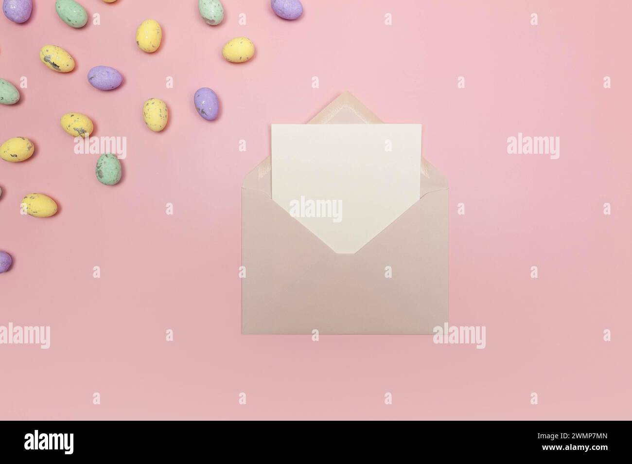 Top view of colourful easter eggs, pink envelope, white card on pink ...