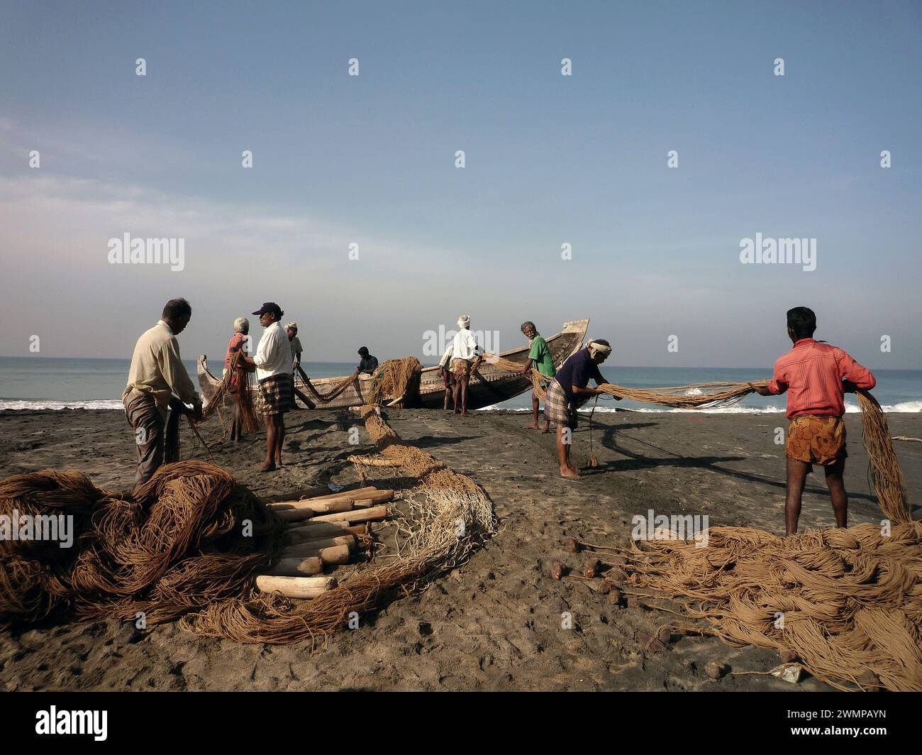 India, Kerala, Varkala: a group of fishermen rewinds fishing nets on ...