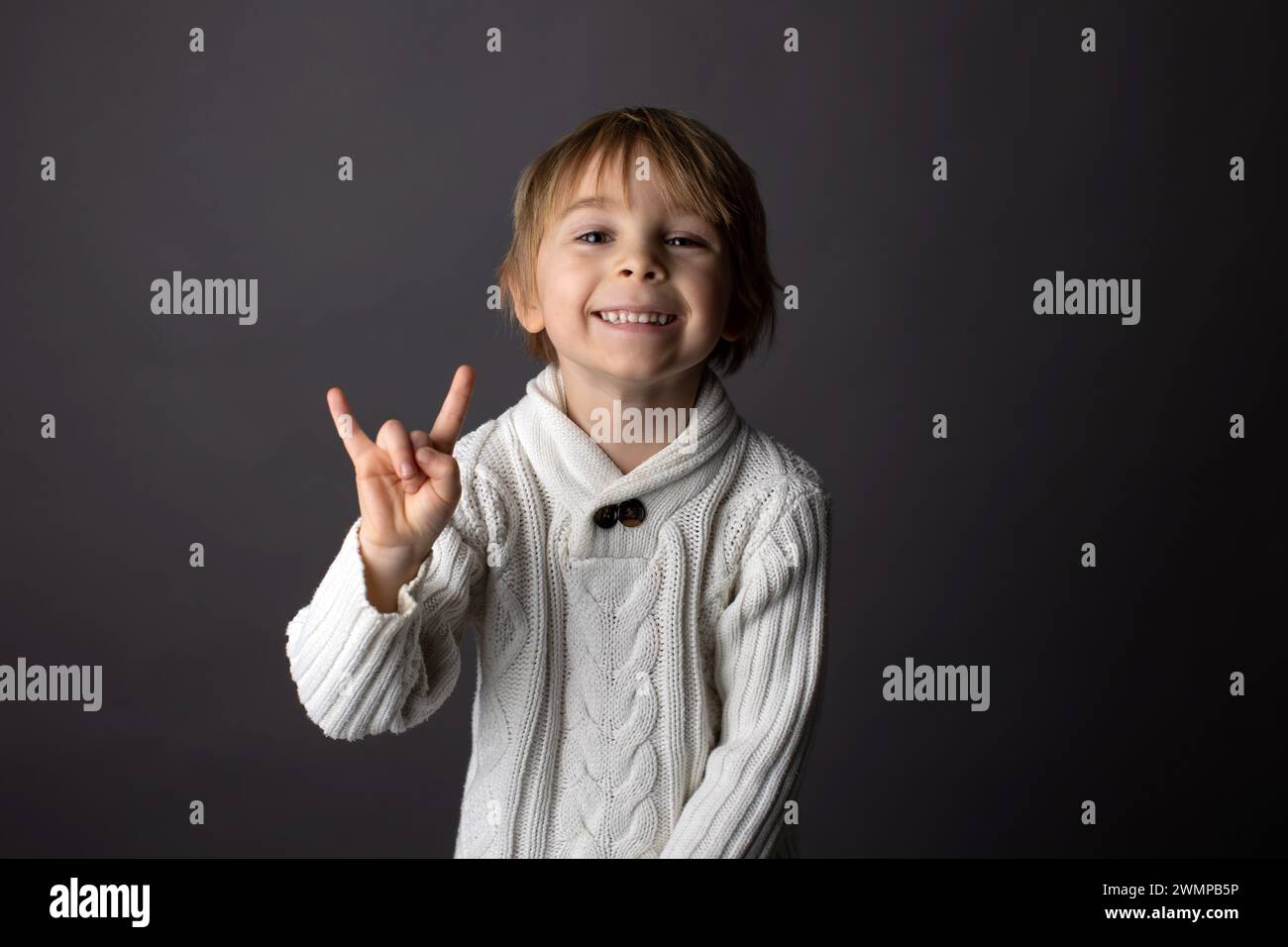 Cute little toddler boy, showing gesture in sign language on gray ...