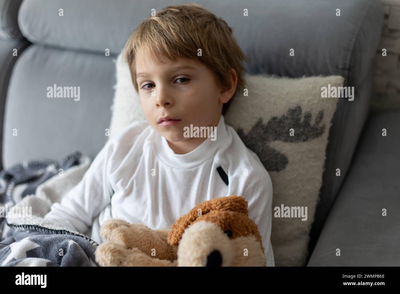 Sick child, toddler boy lying in bed with a fever, resting at home with ...