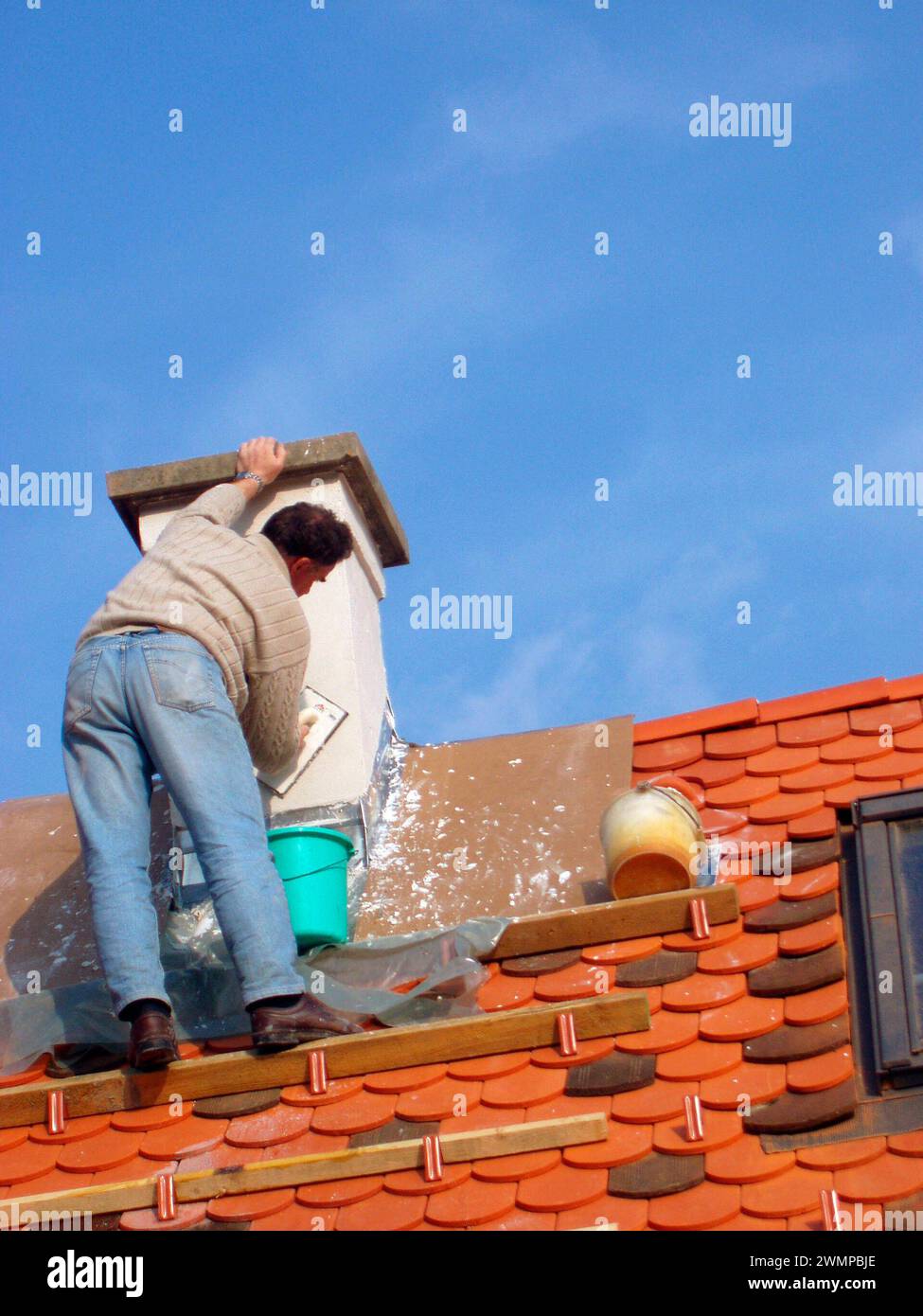 chimney renovation on a building, worker standing on a roof chimney ...