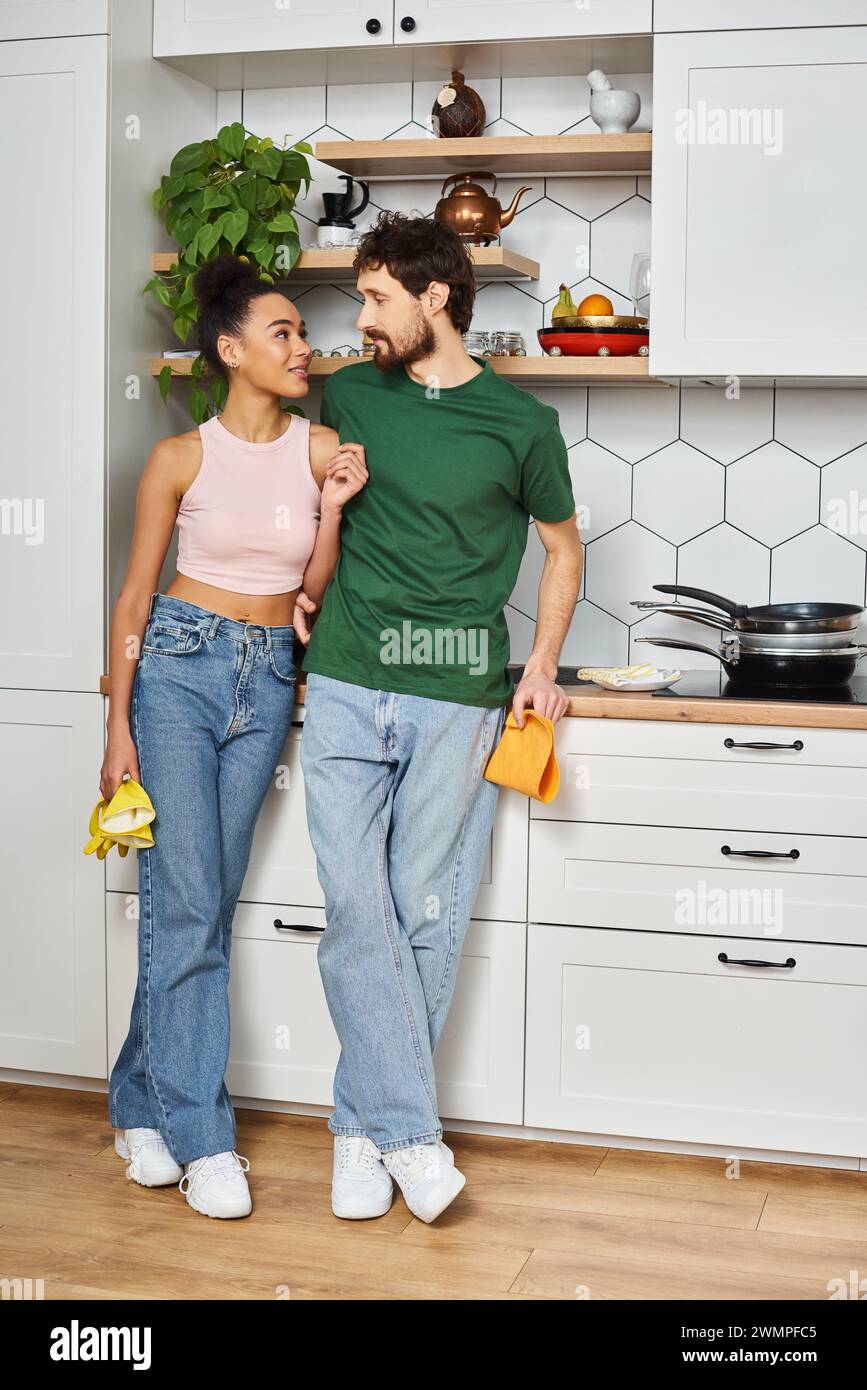 loving multicultural jolly couple in comfy attires with gloves and rags ...