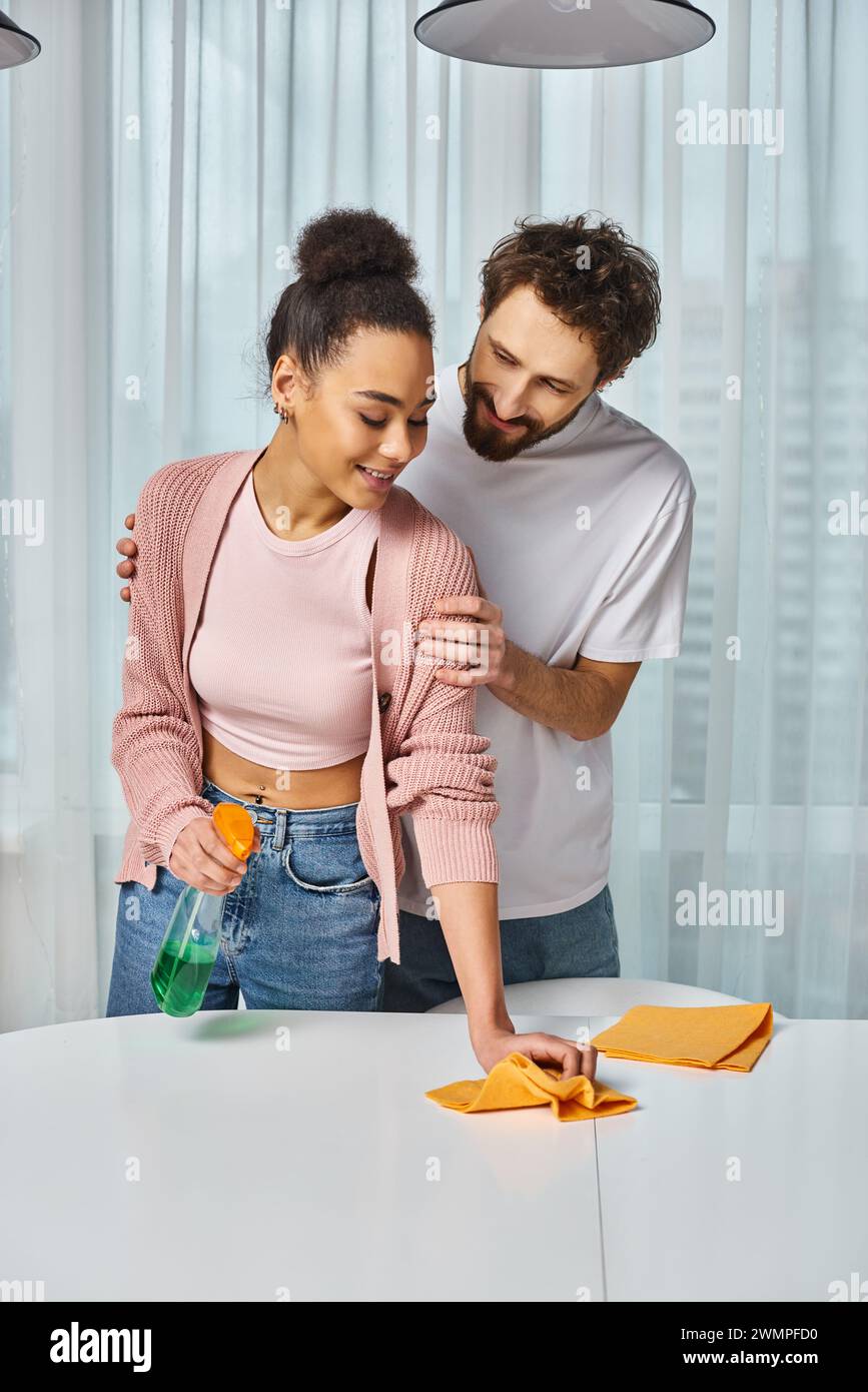 good looking multiracial jolly couple in homewear cleaning together at ...