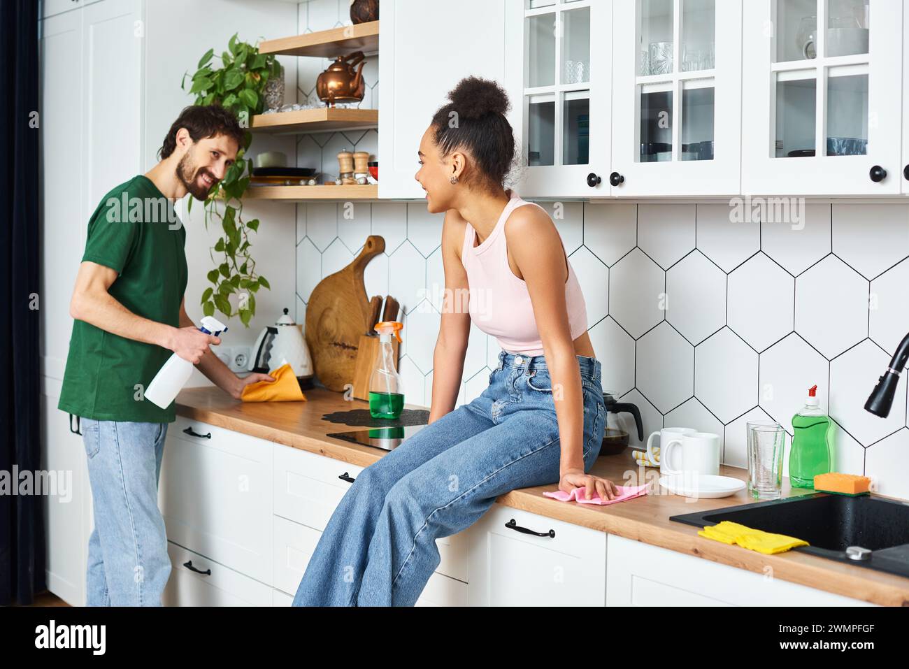 cheerful african american woman sitting on counter and looking at her ...