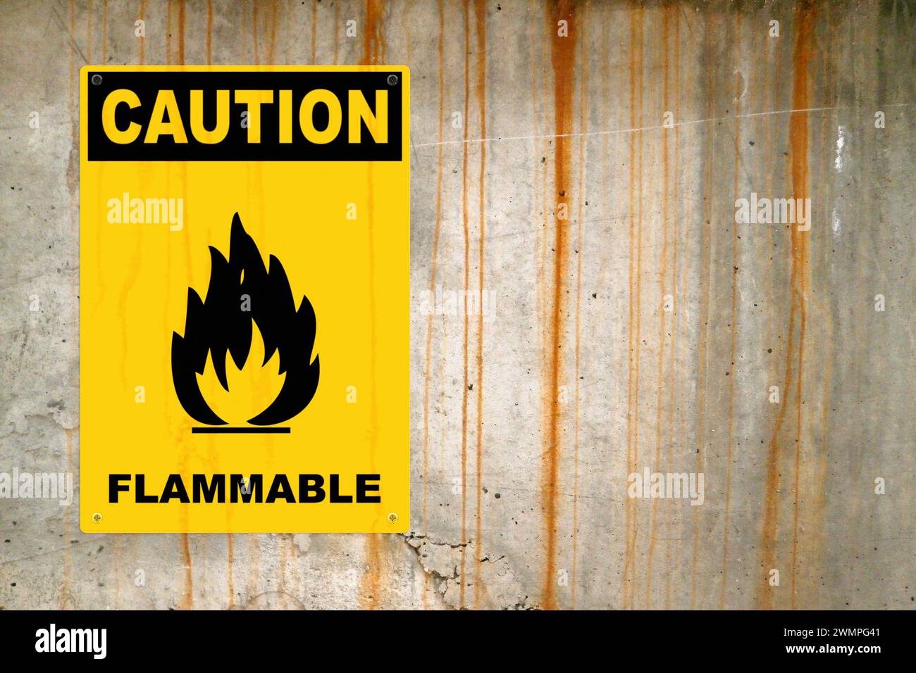 Yellow warning sign screwed to a concrete wall to warn about a threat ...