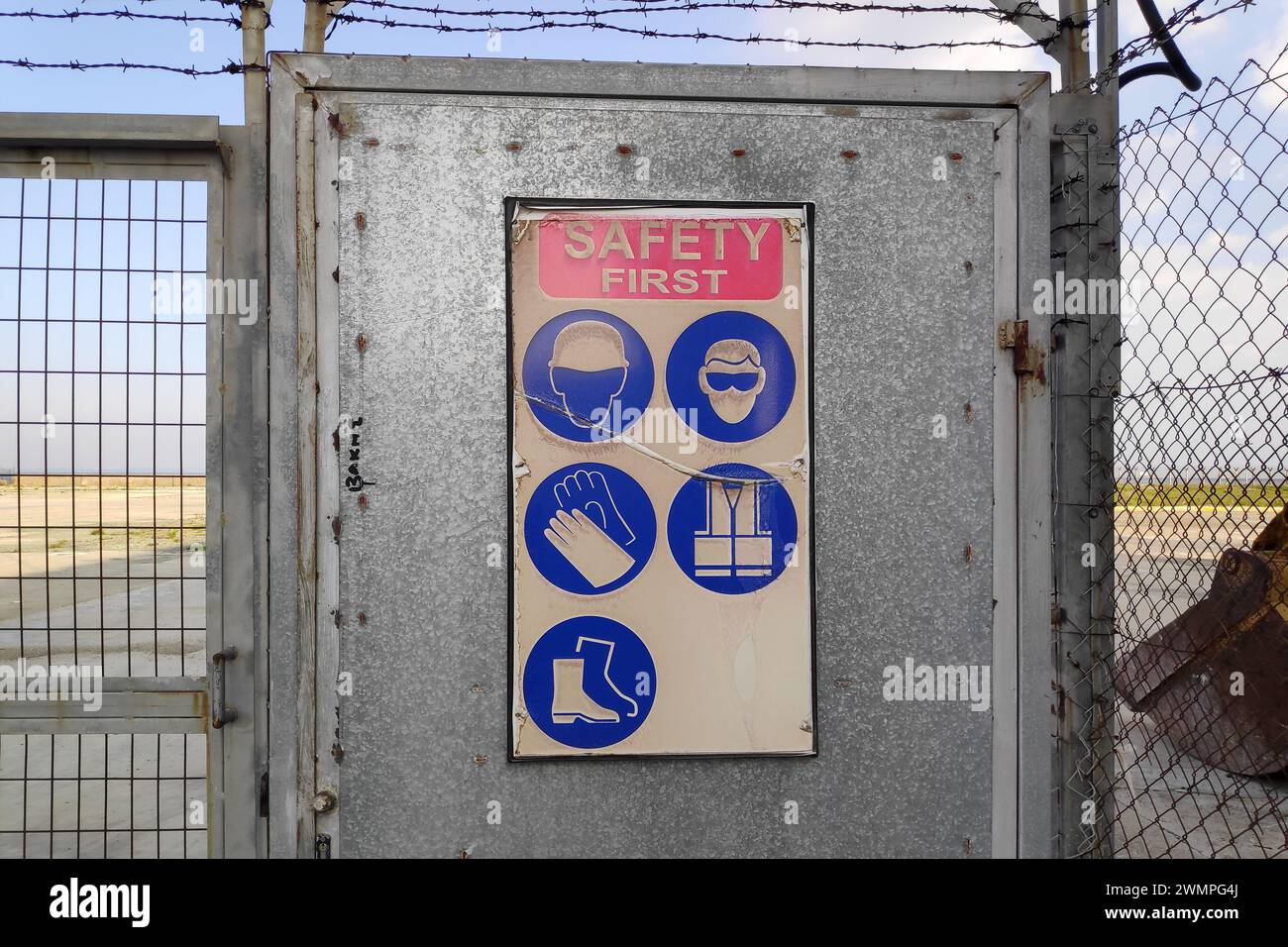 Sign attached to the metal gate of an industrial site by the sea ...