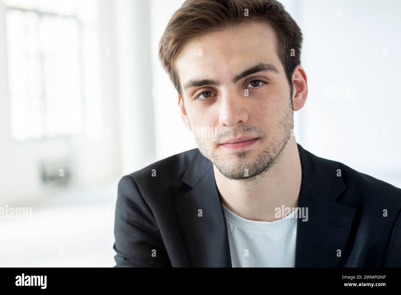 Portrait of a boy with a stubbled beard wearing a black jacket and a ...