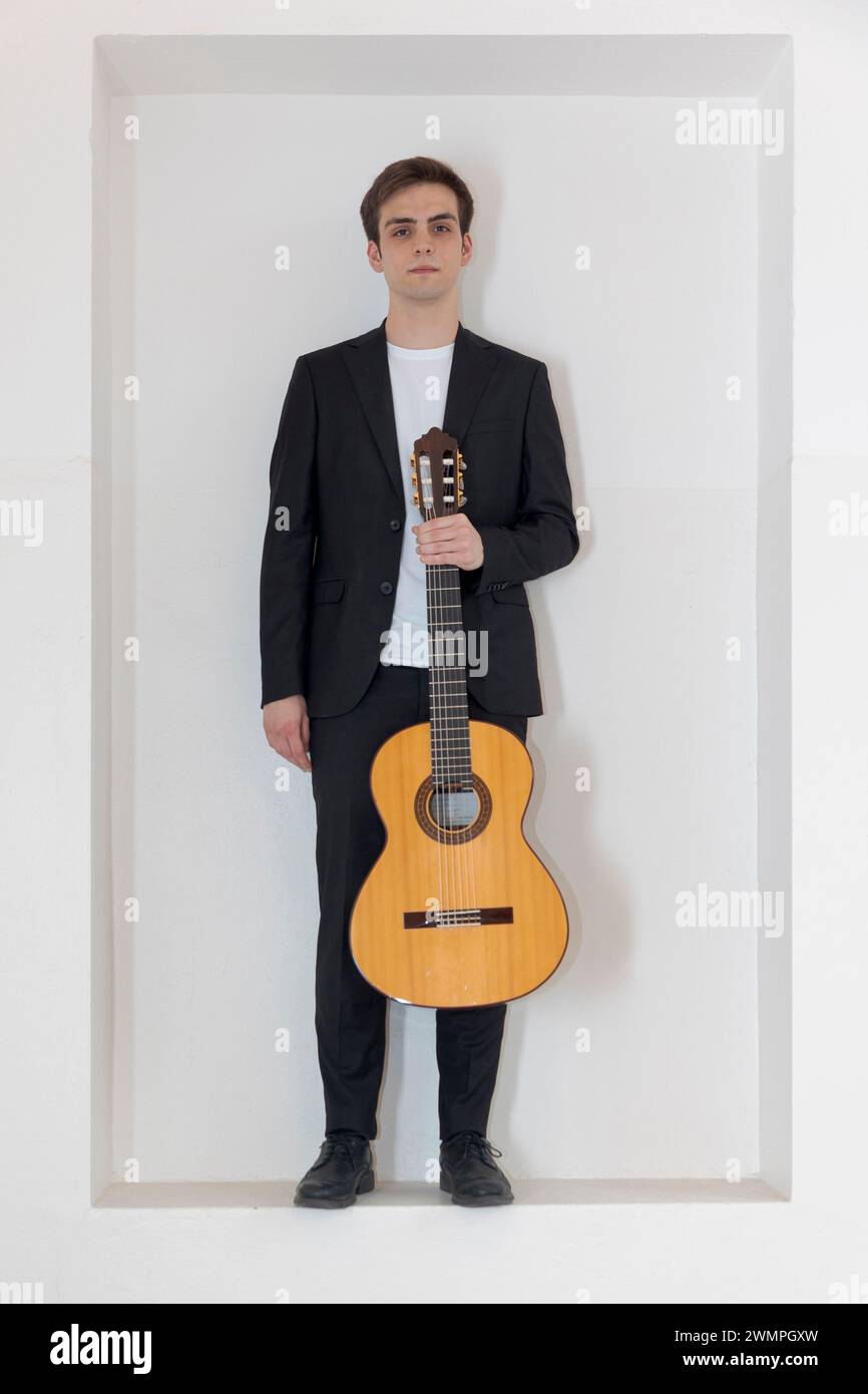 A young boy in an elegant suit stands in a niche in the wall. With one ...