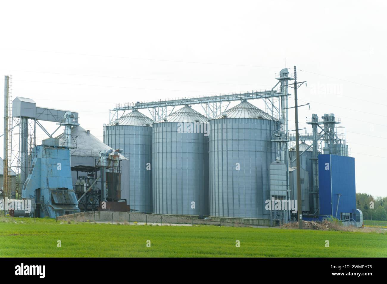 A modern agricultural setup featuring tall metal grain silos connected ...
